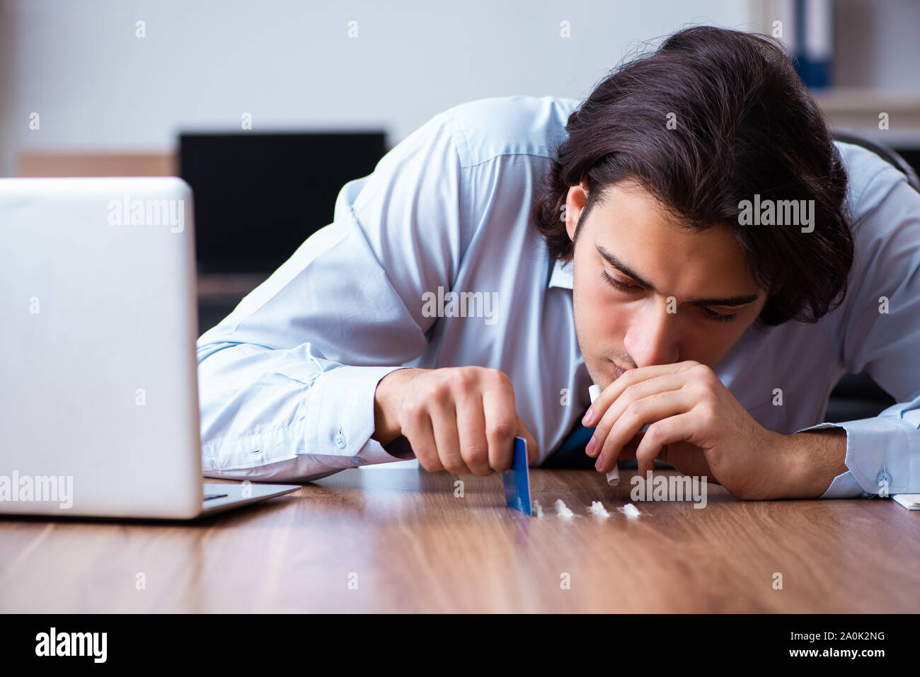 The young man having problems with narcotics at workplace Stock Photo ...