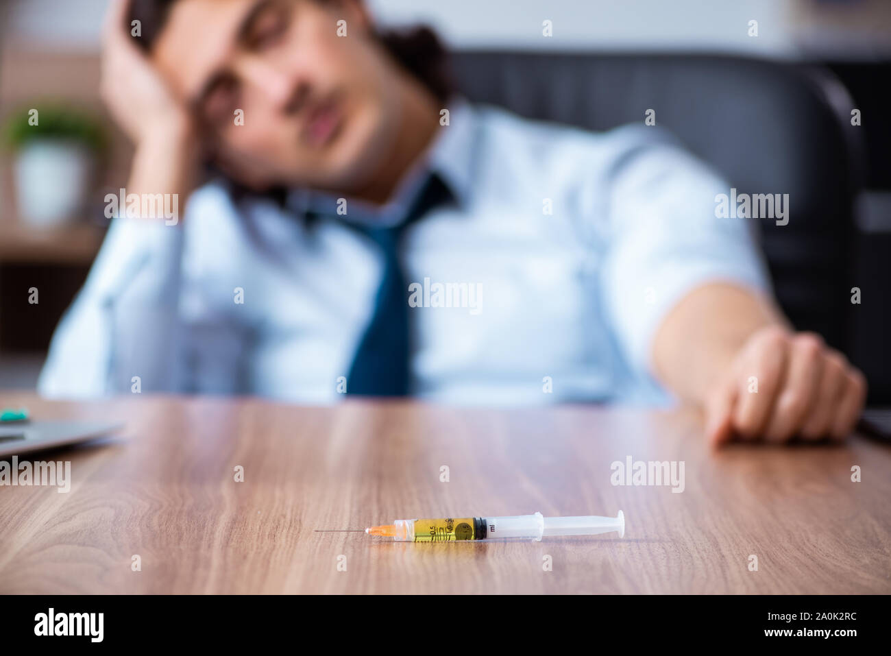 The young man having problems with narcotics at workplace Stock Photo ...