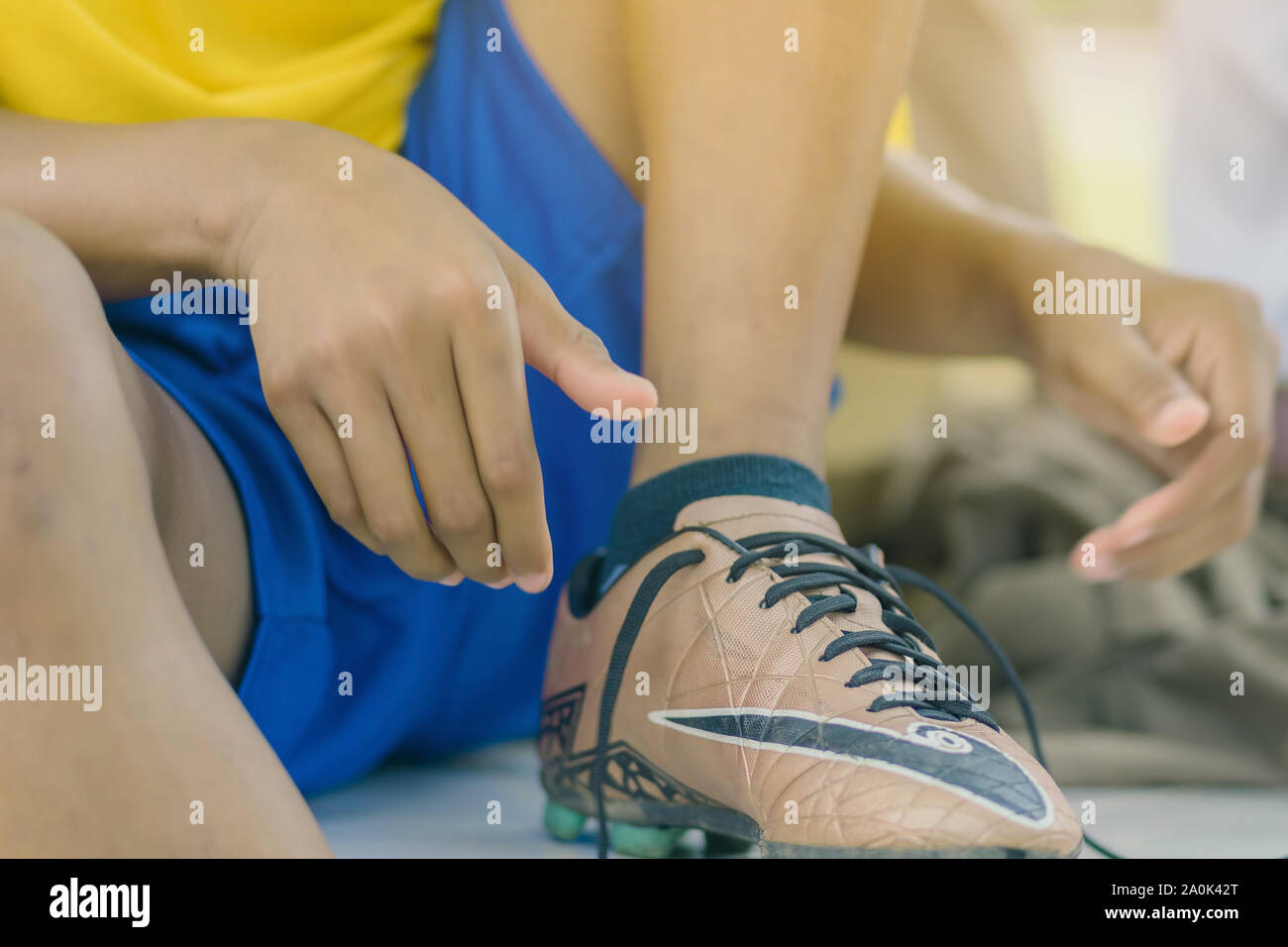 Close up to Young man sit to tying studded laces before play soccer ...