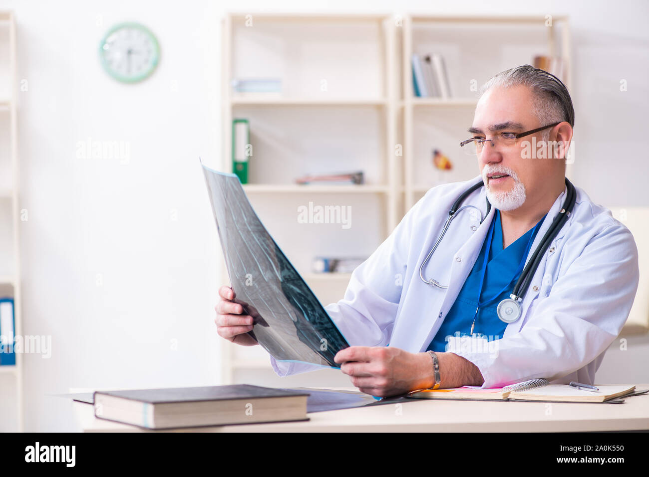 The old male doctor working in the clinic Stock Photo - Alamy