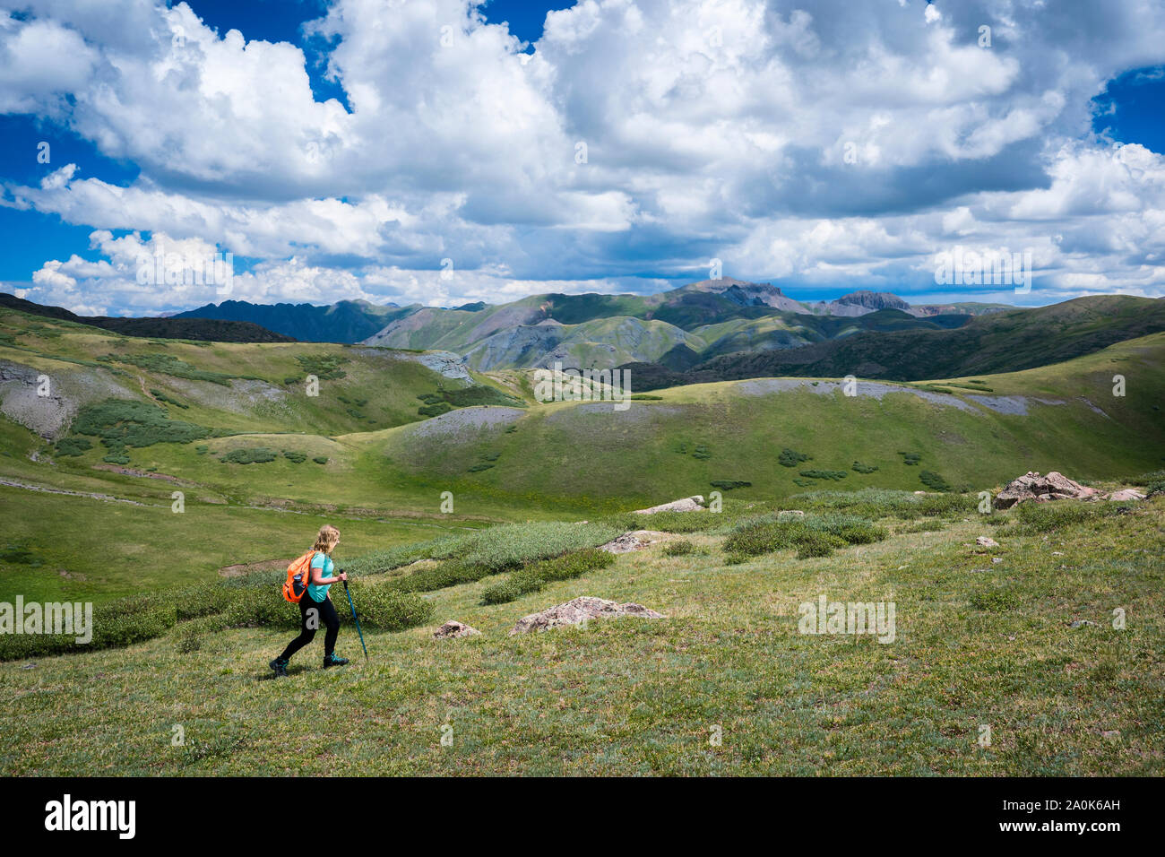 Blond teenage girl hiking in mountains above tree line in the San Juan ...
