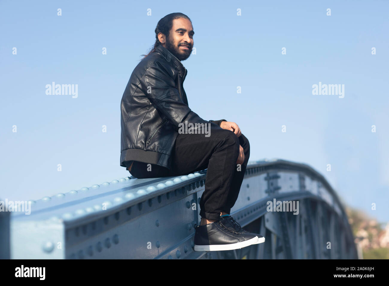 young man with braid and beard sitting on a bridge Stock Photo - Alamy