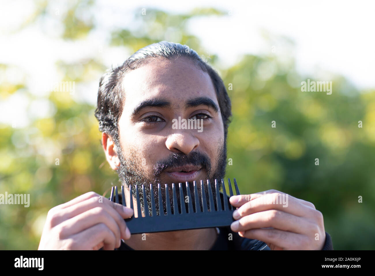 young man with braid and beard singing with comb Stock Photo - Alamy