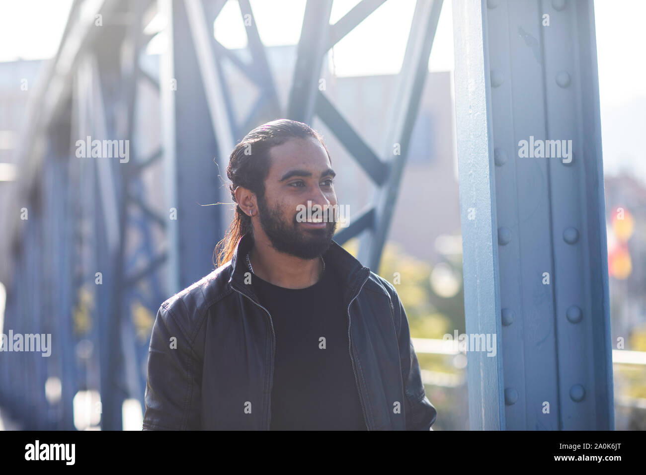 young man with braid and beard walking on a steel bridge Stock Photo ...