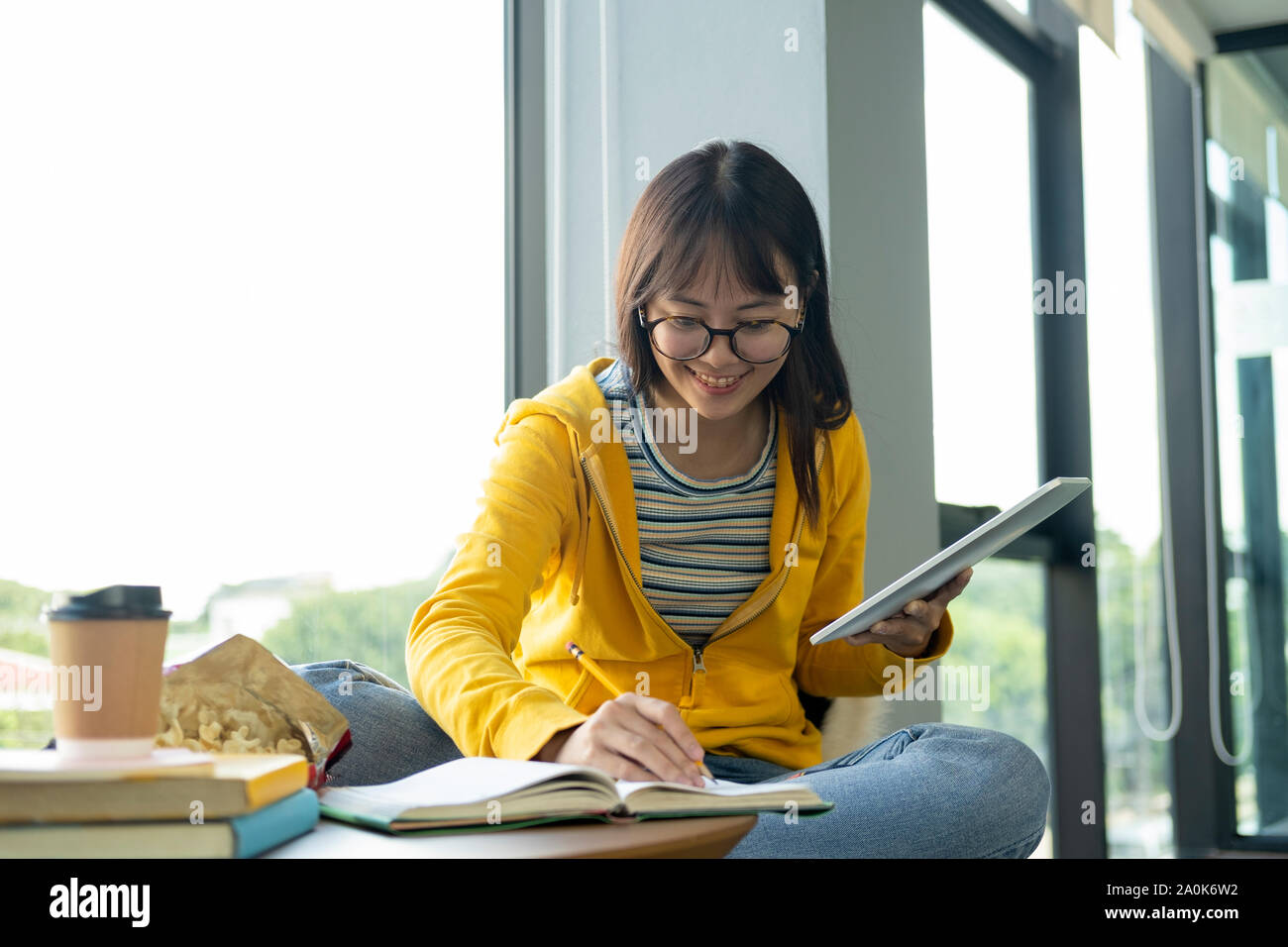 Young collage student using computer and mobile device studying online ...