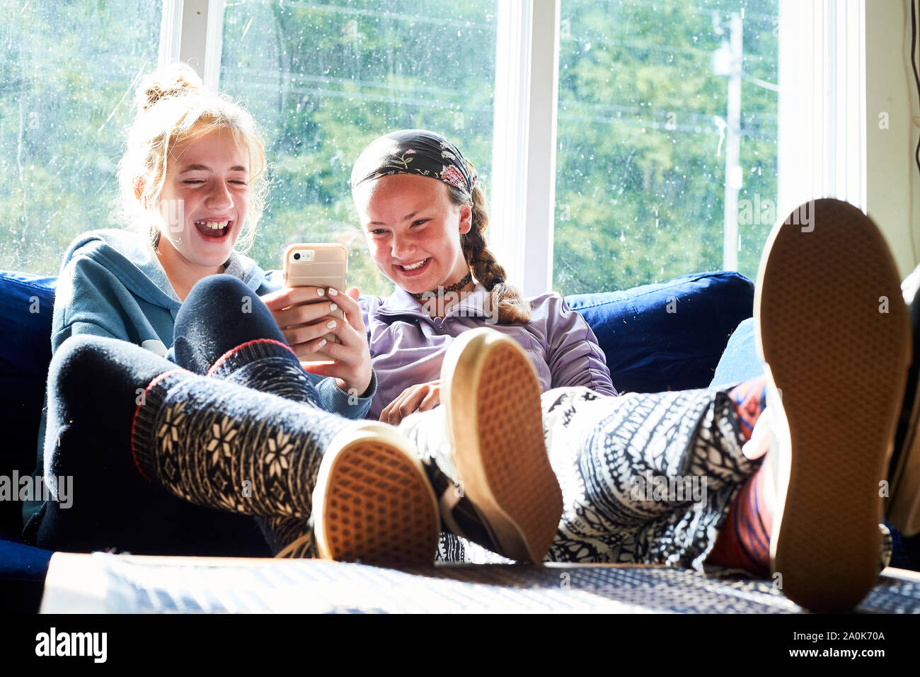 Teen girls laughing on a couch looking at something on a phone Stock ...