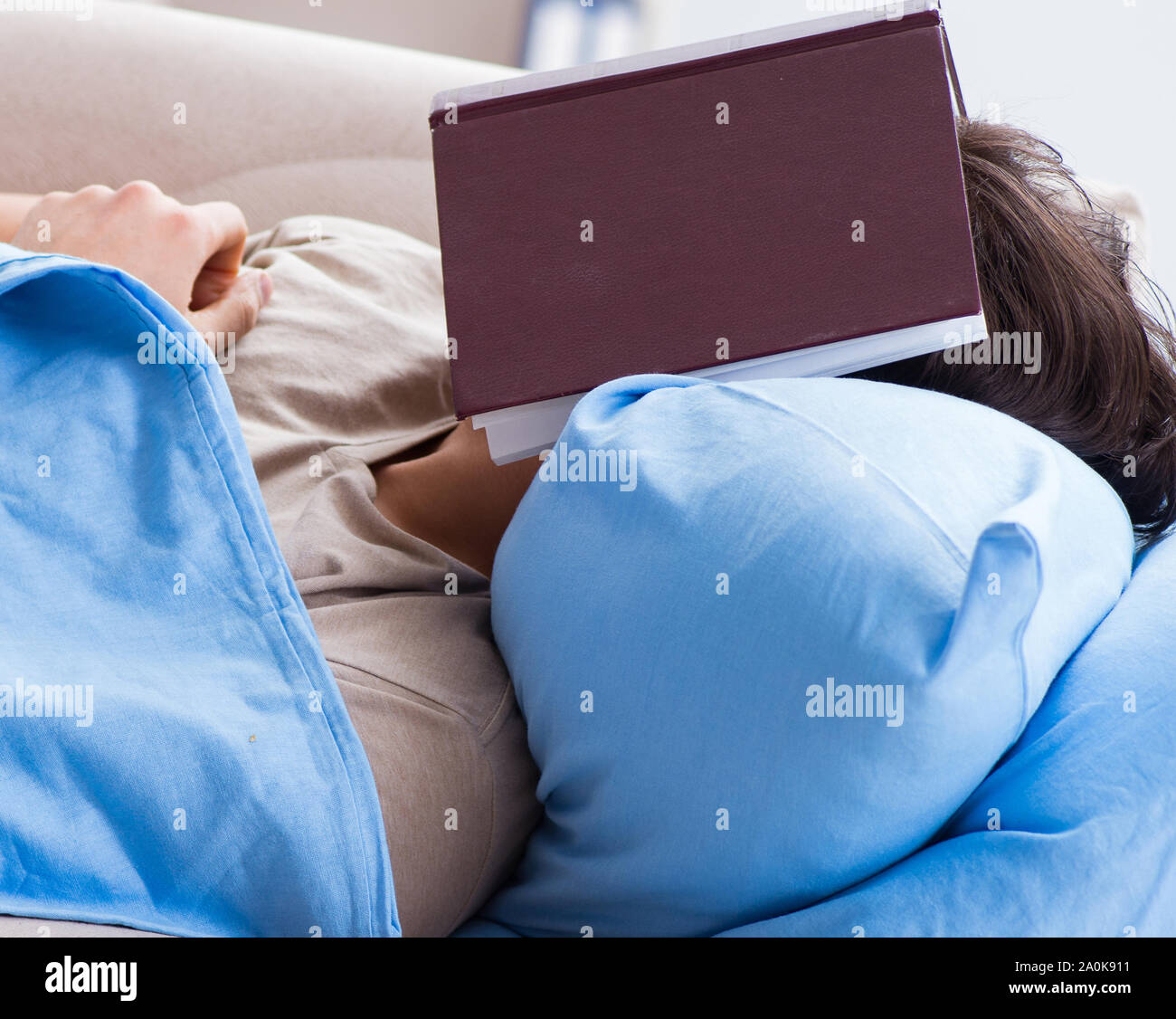 The young student man preparing for college exams in bed with book ...