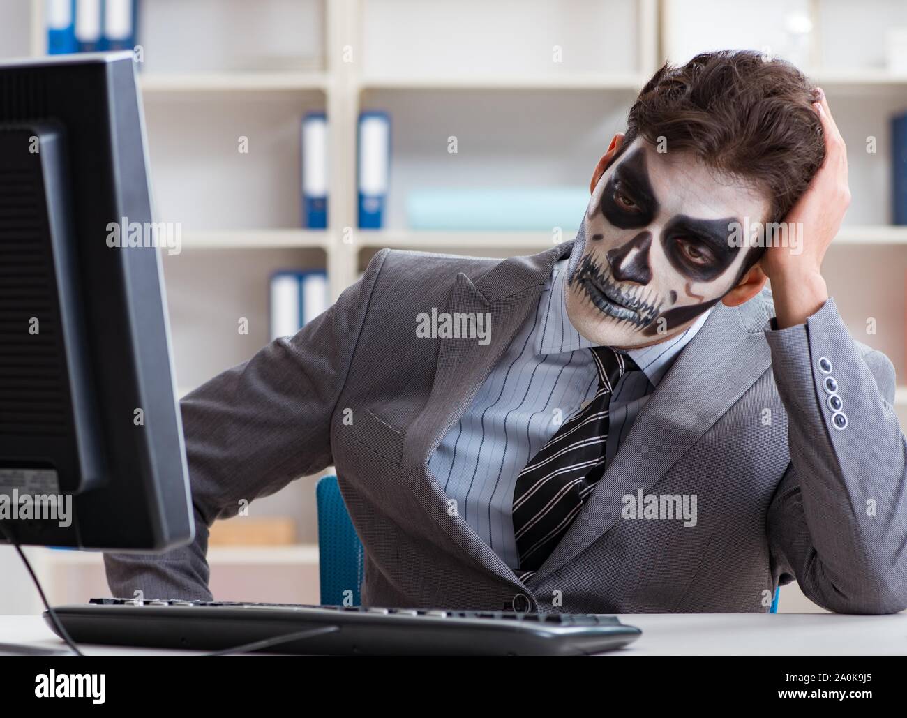Businessman with scary face mask working in office Stock Photo - Alamy