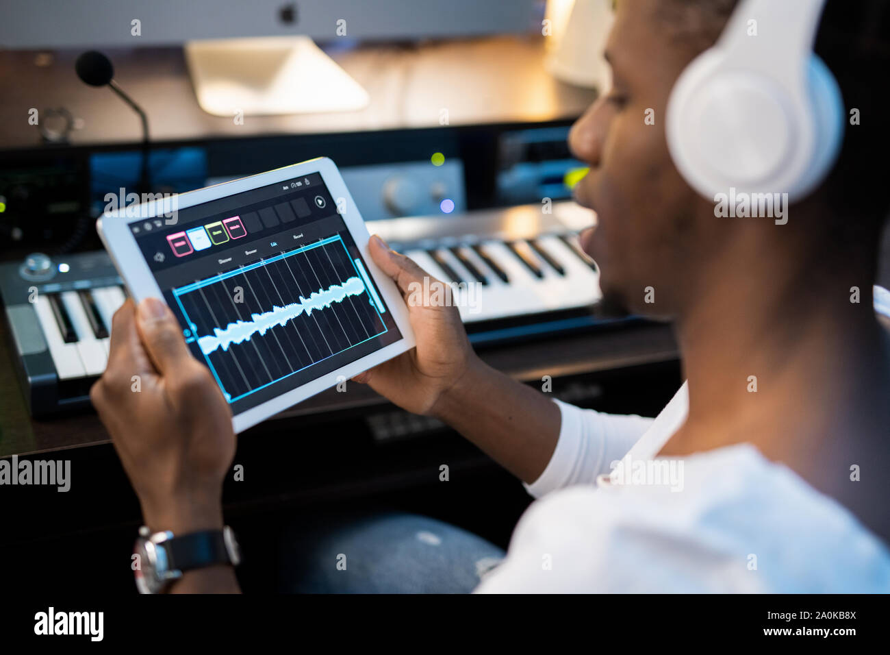 African-american young man with headphones holding tablet with sound ...