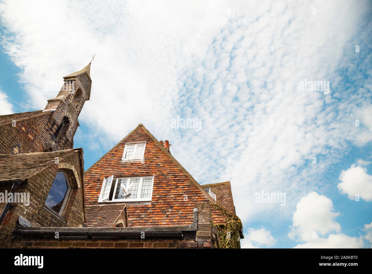 Rooftop of an old historic church and tiled facade house, blue cloudy ...