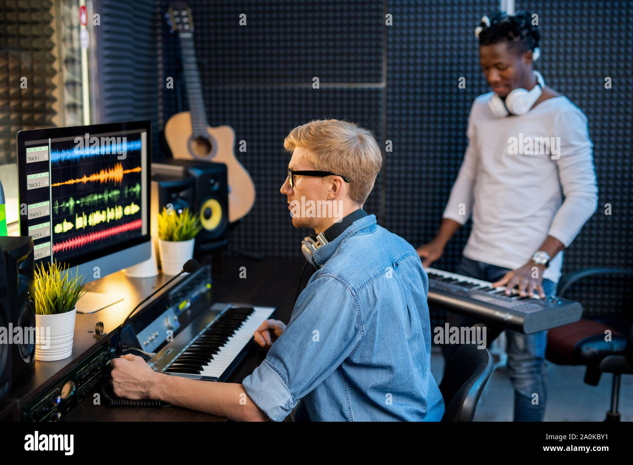 Serious man in denim shirt working with sound waveforms in studio of ...