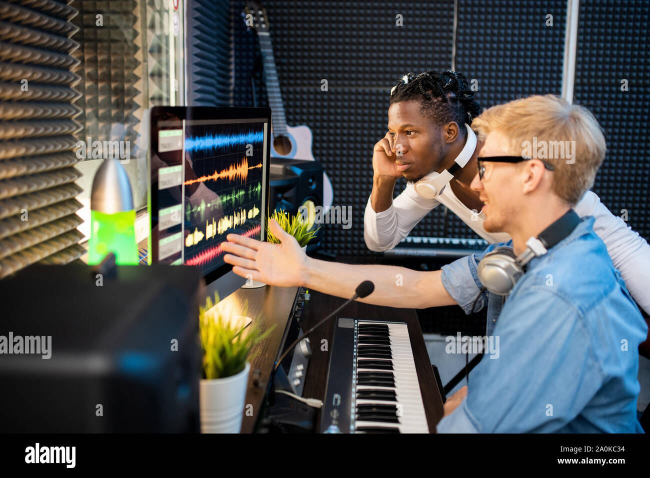 Young musicians looking at computer screen during discussion of sound ...