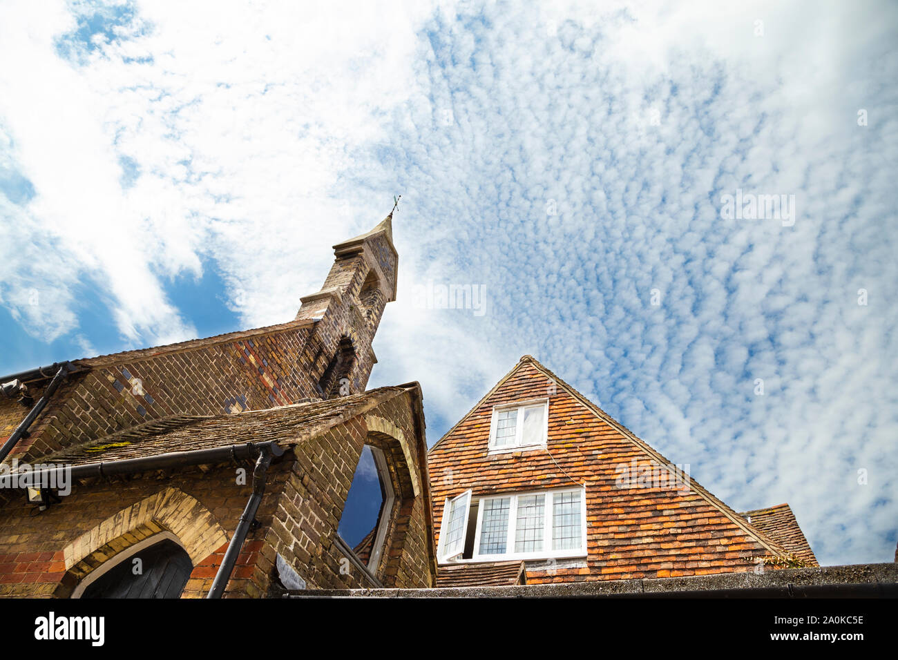 Rooftop of an old historic church and tiled facade house, blue cloudy ...