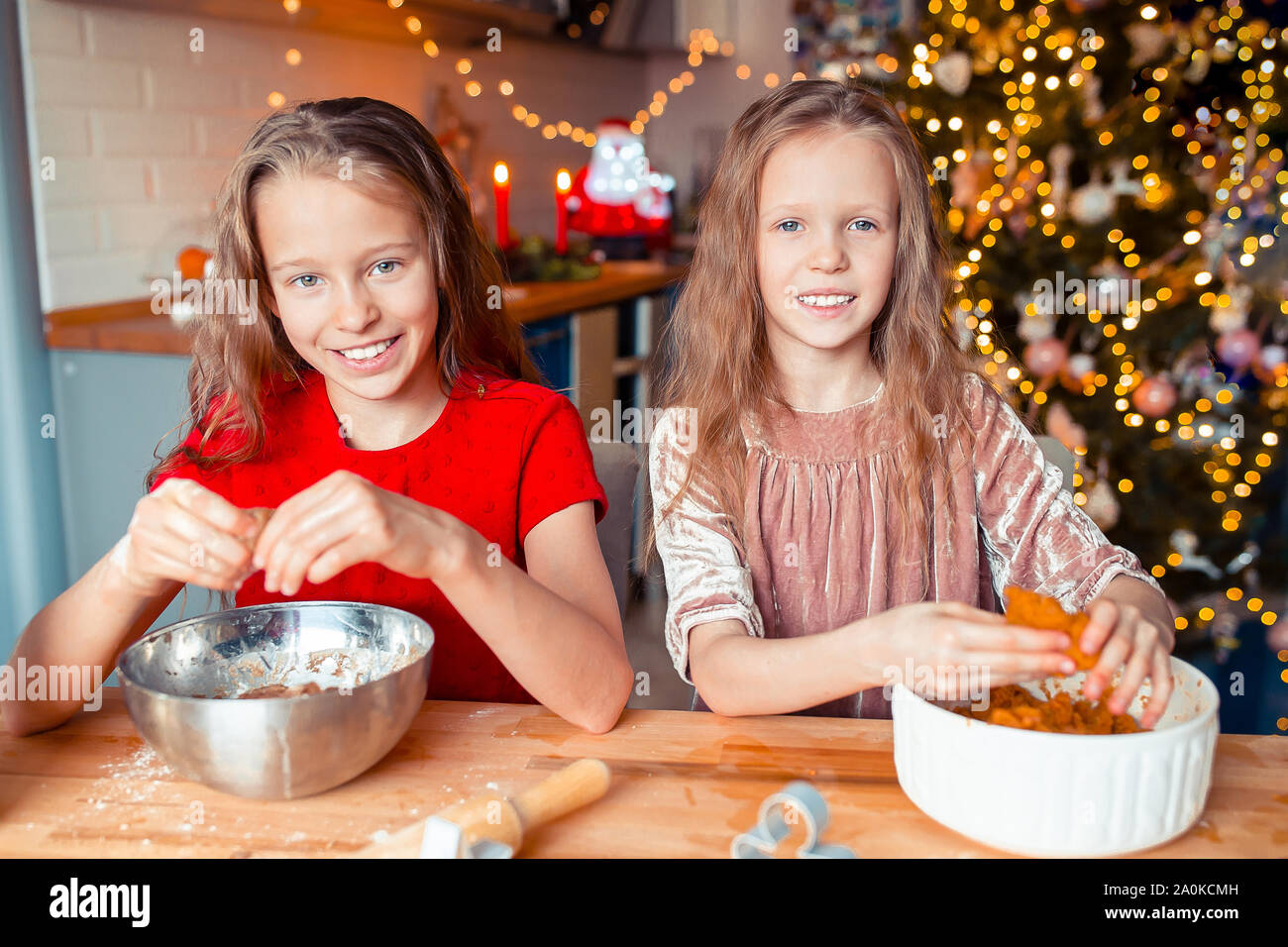 Adorable little girls baking cookies background of lights and Christmas ...