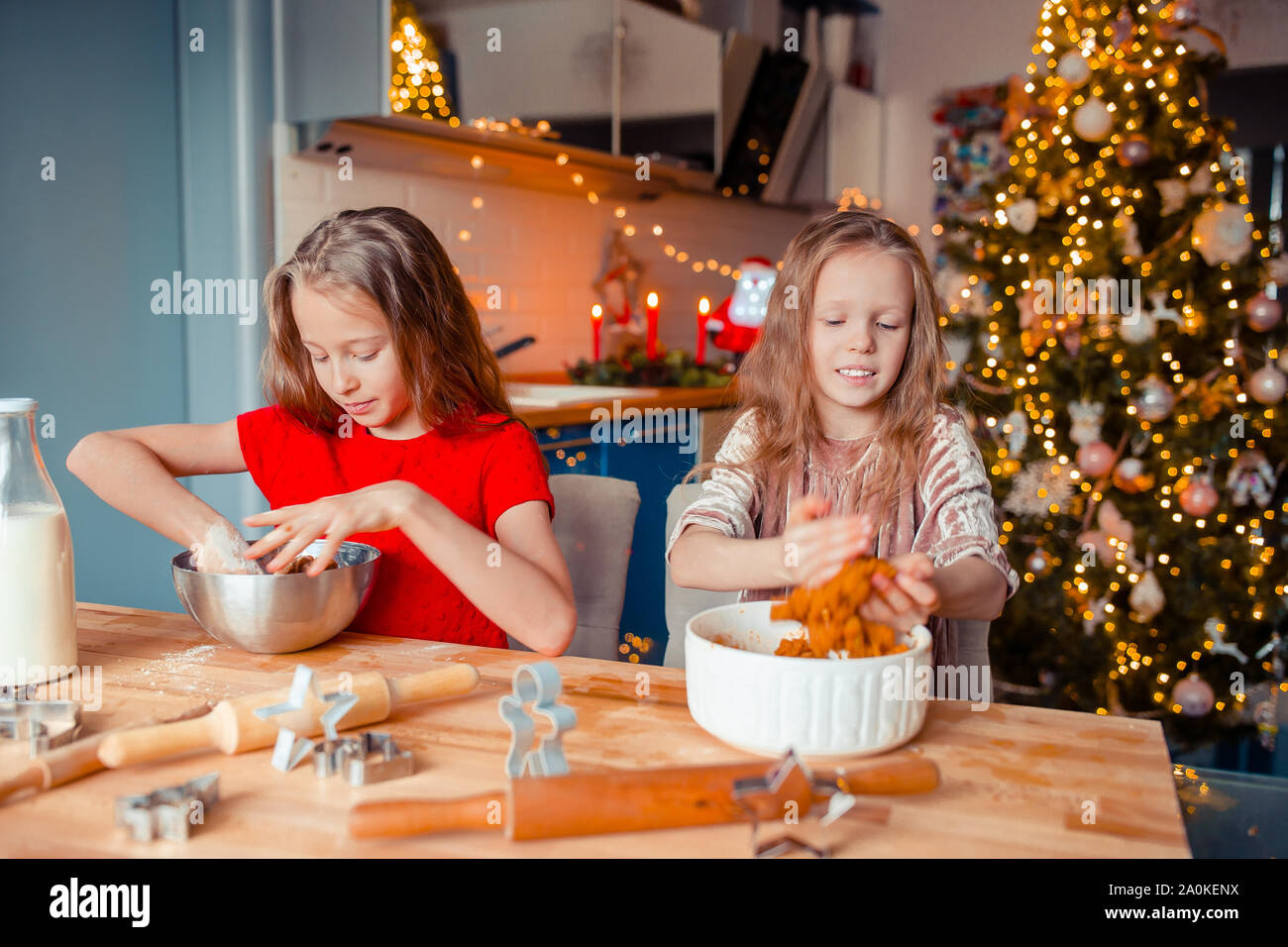 Adorable little girls baking cookies background of lights and Christmas ...