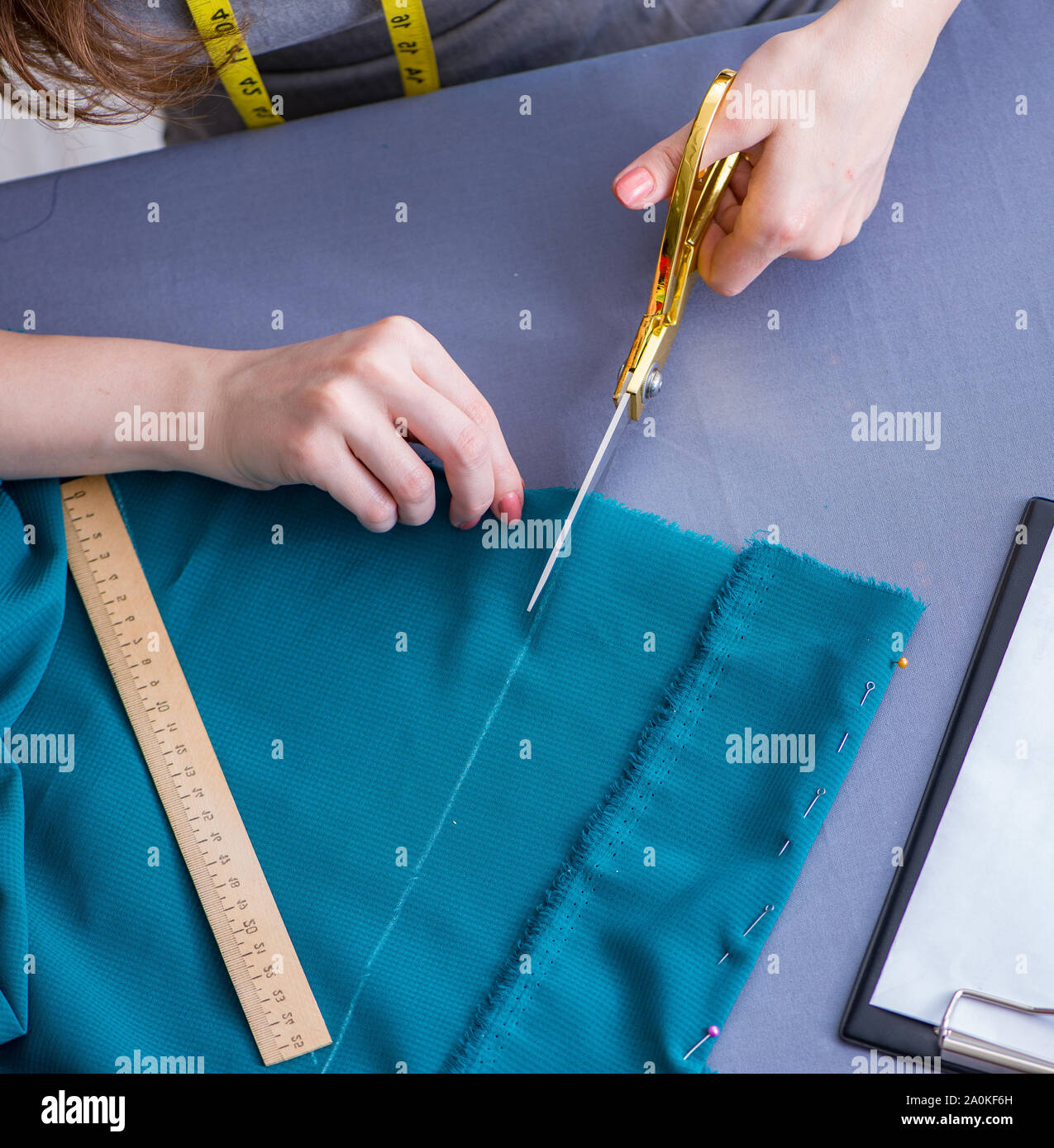 Woman tailor working on a clothing sewing stitching measuring fabric ...