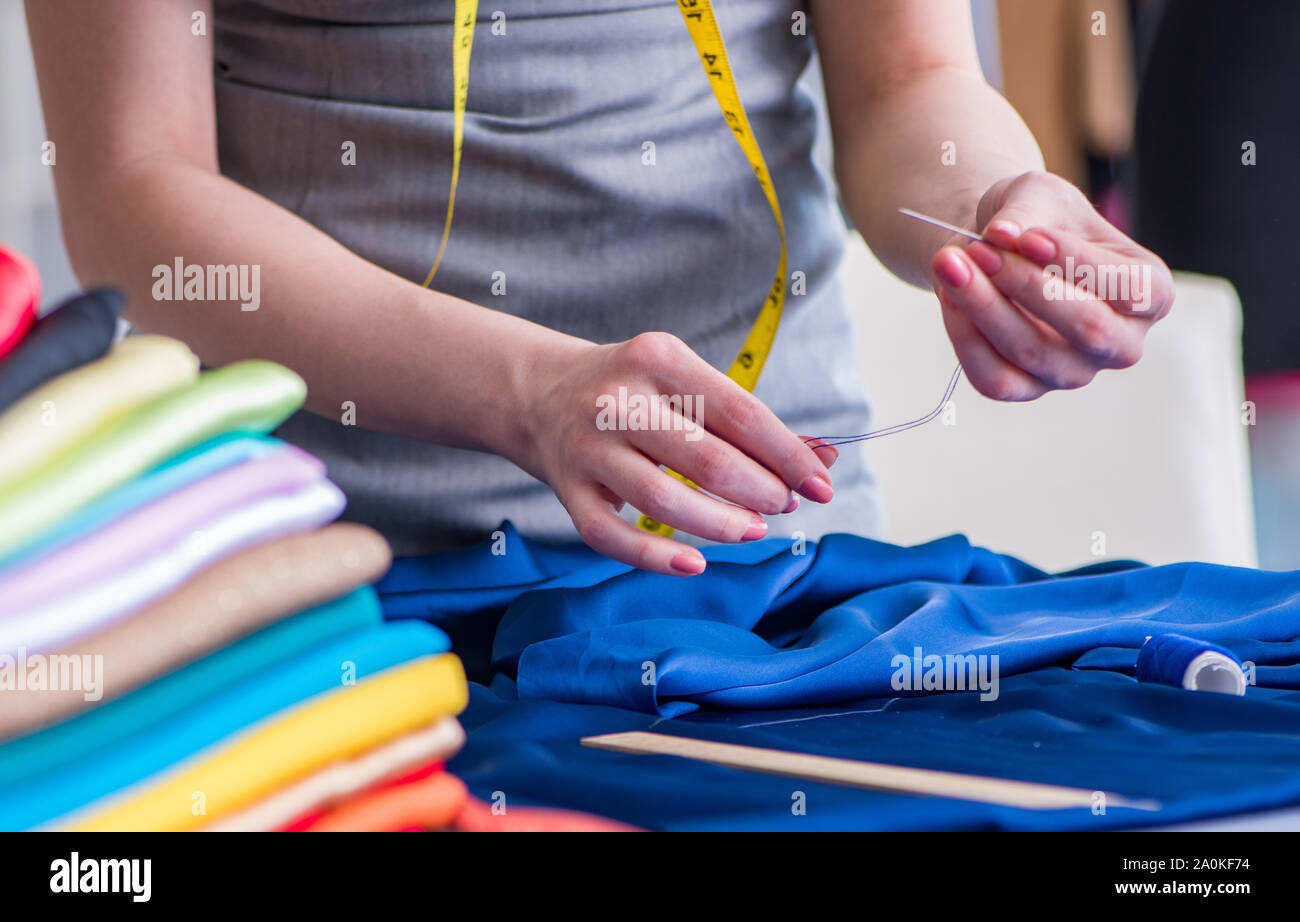 Woman tailor working on a clothing sewing stitching measuring fabric ...