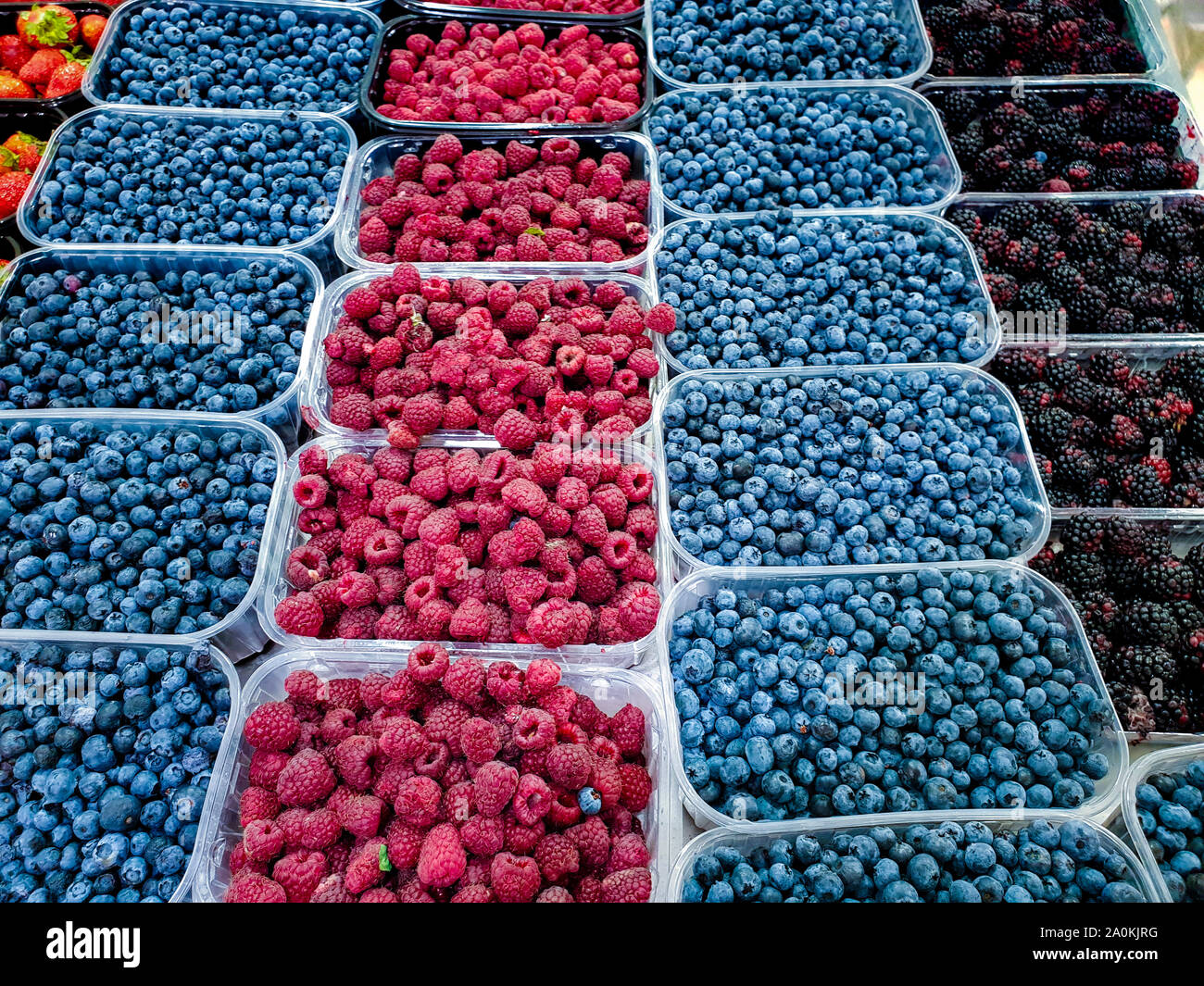 Various fresh berries Fruits in Plastic Trays on food market stall ...