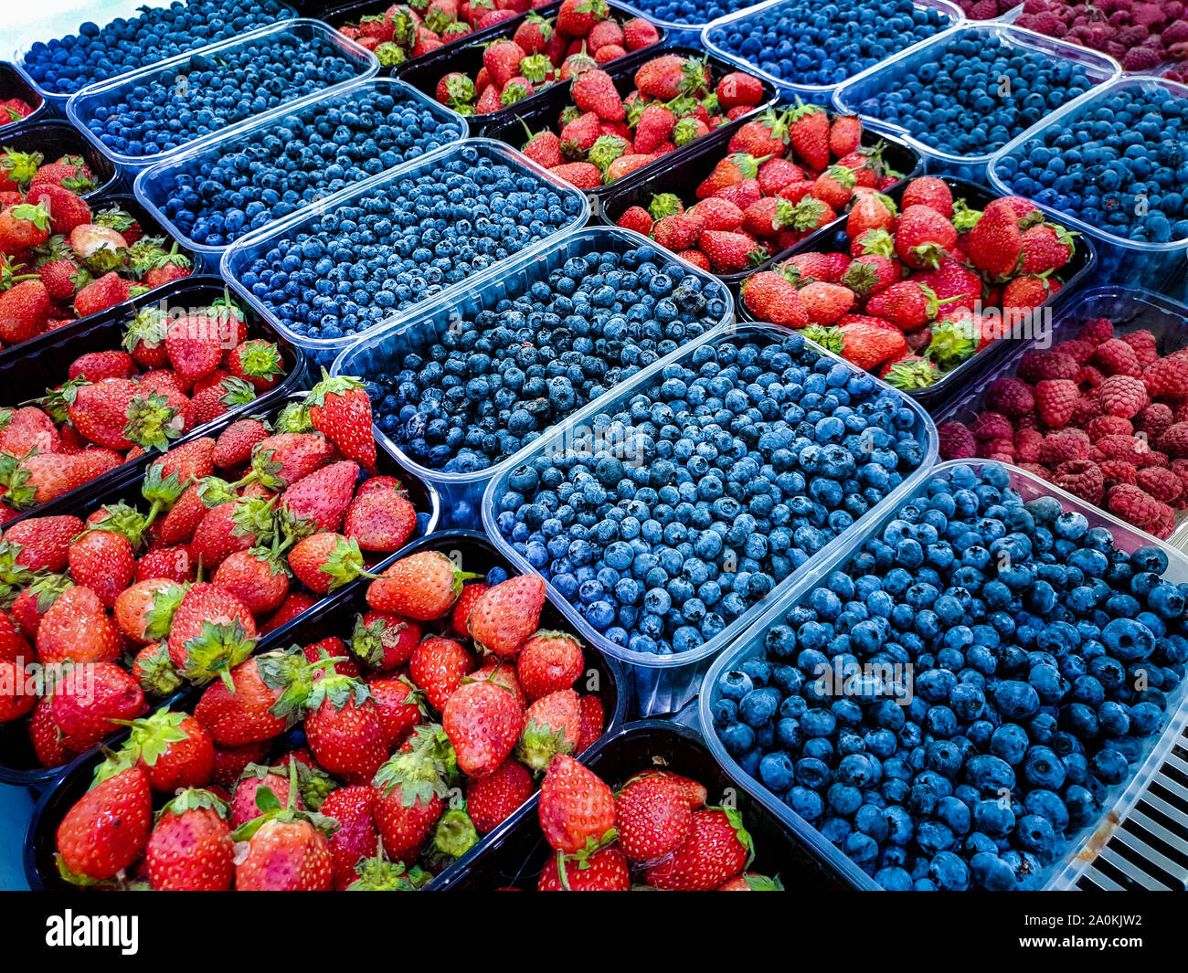 Various fresh berries Fruits in Plastic Trays on food market stall ...