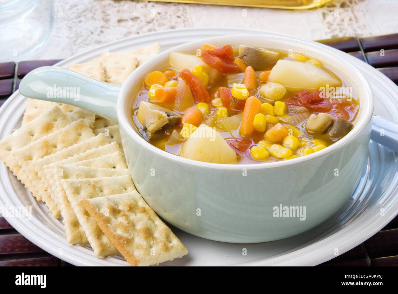 Warm homemade vegetable soup and served with crispy saltine crackers in ...