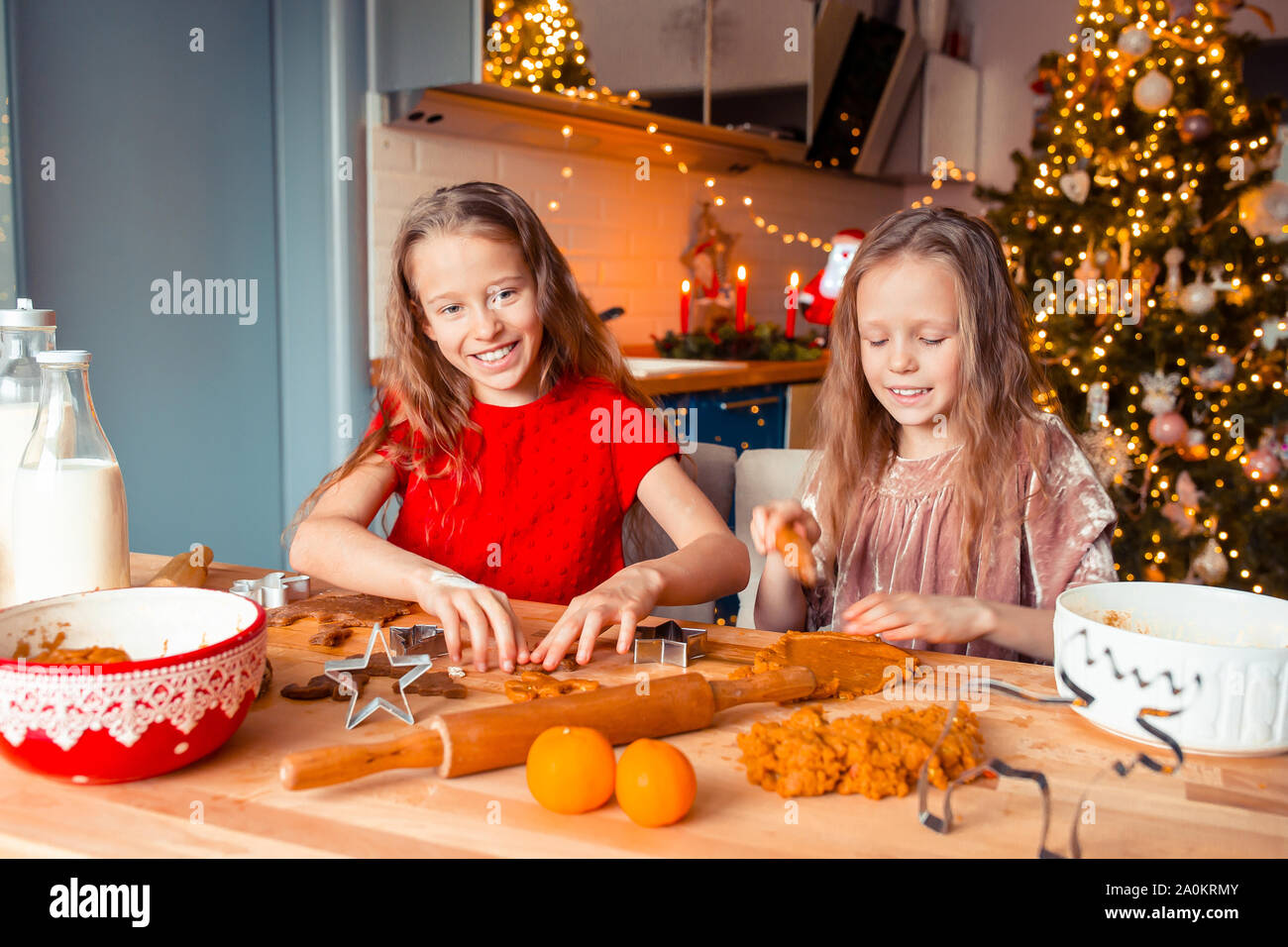Adorable little girls baking cookies background of lights and Christmas ...