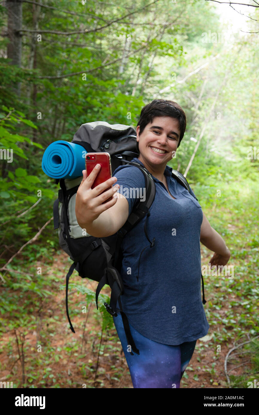 happy looking millennial poses for a selfie while showing off camping ...