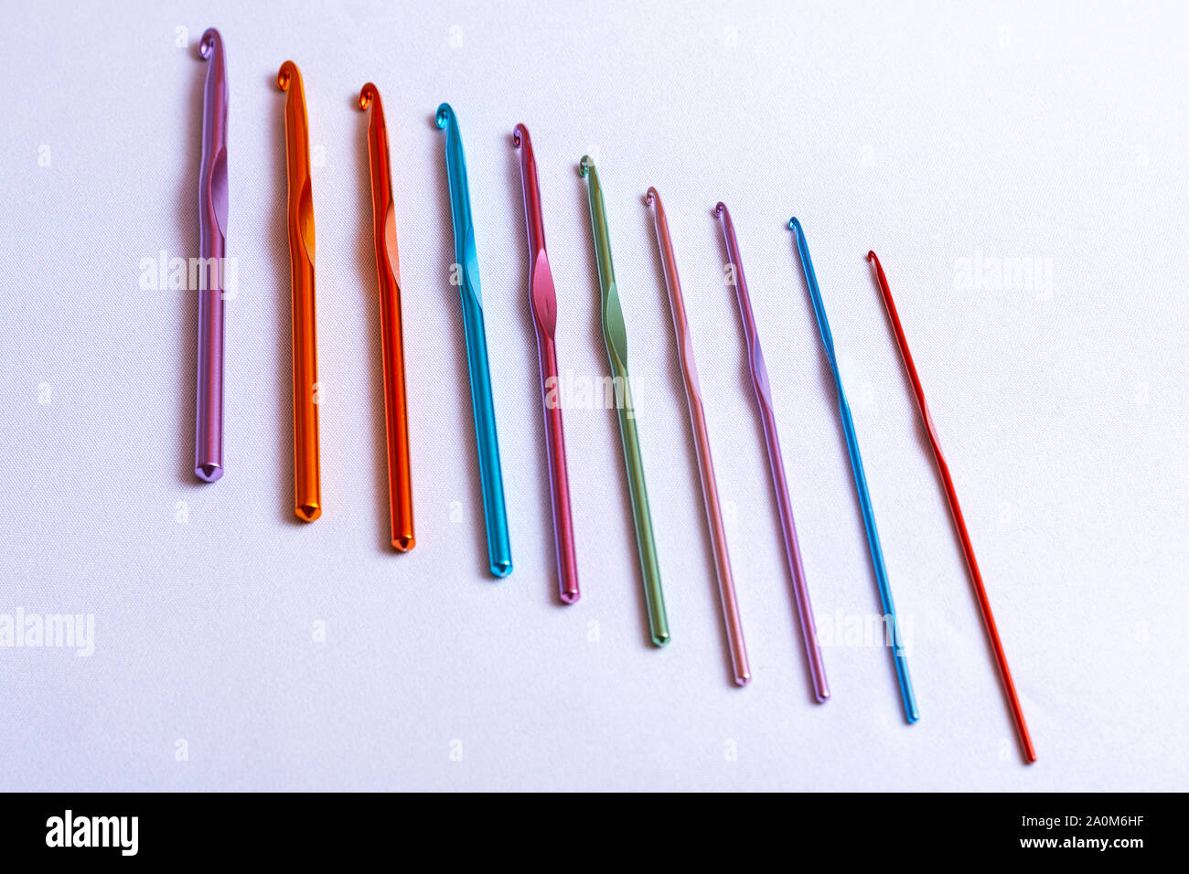 Crochet hooks of different sizes and colors arranged in one row ...