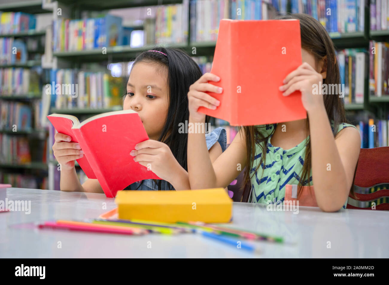 Two little cute girls multi-ethnic friends reading books together in ...
