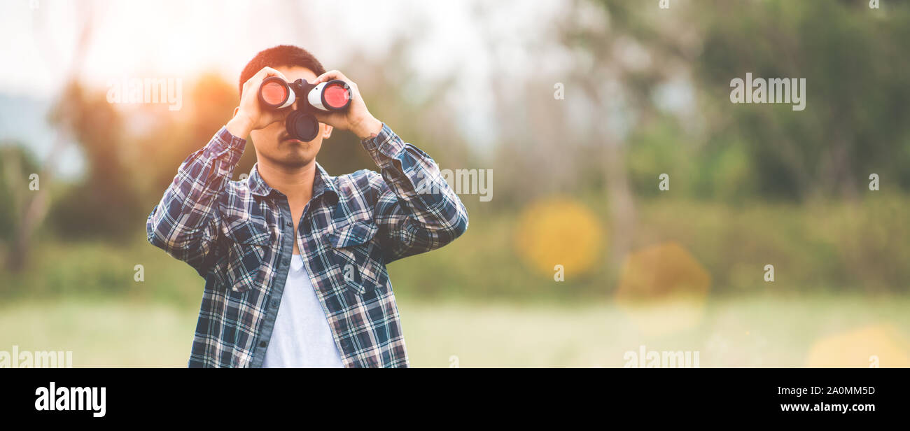 Man with binoculars telescope in forest looking destination as lost people or foreseeable future ...