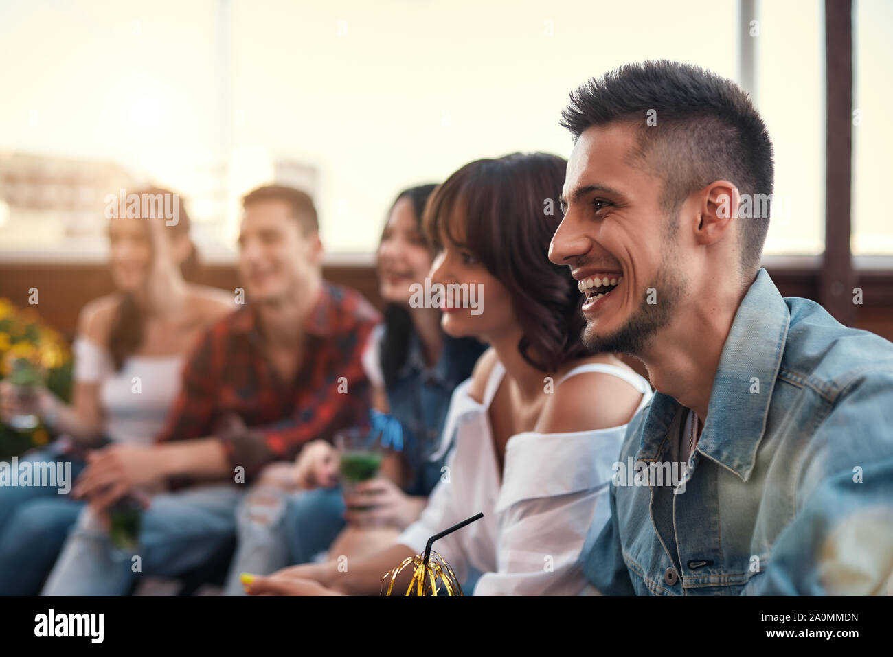 Group of young smiling people drinking cocktails and relaxing on ...