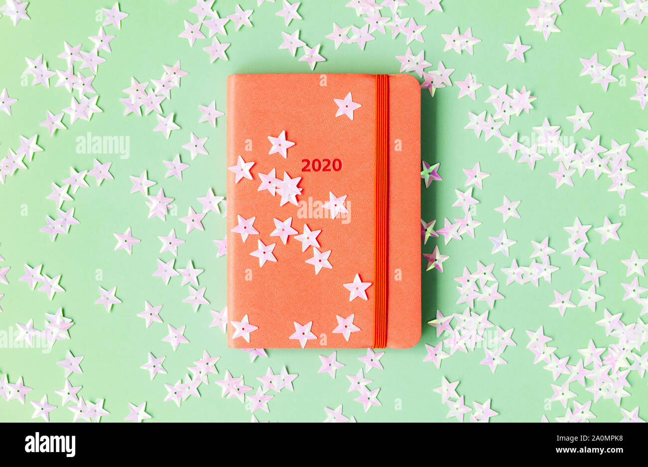 Orange diary for 2020 on a mint background strewn with light pink stars ...
