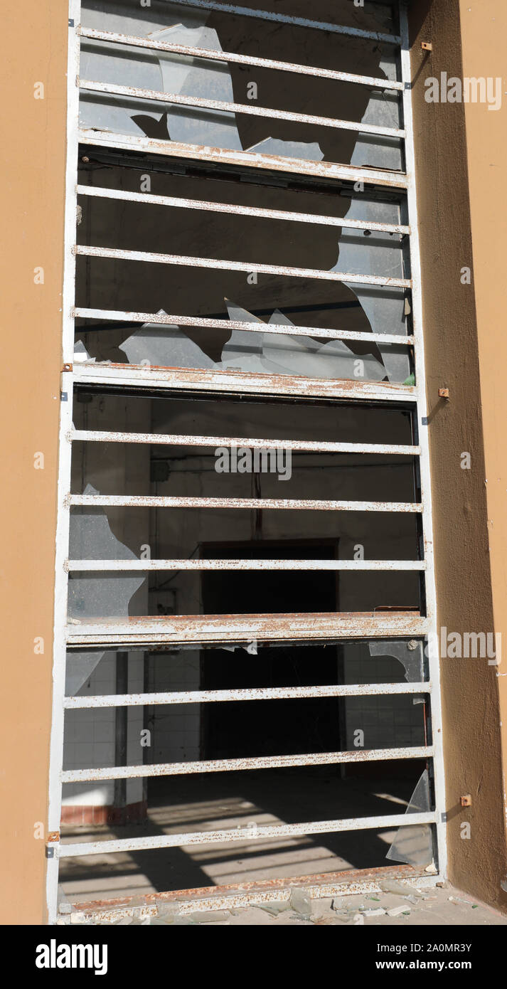 large window with glass completely broken by vandals and iron bars ...