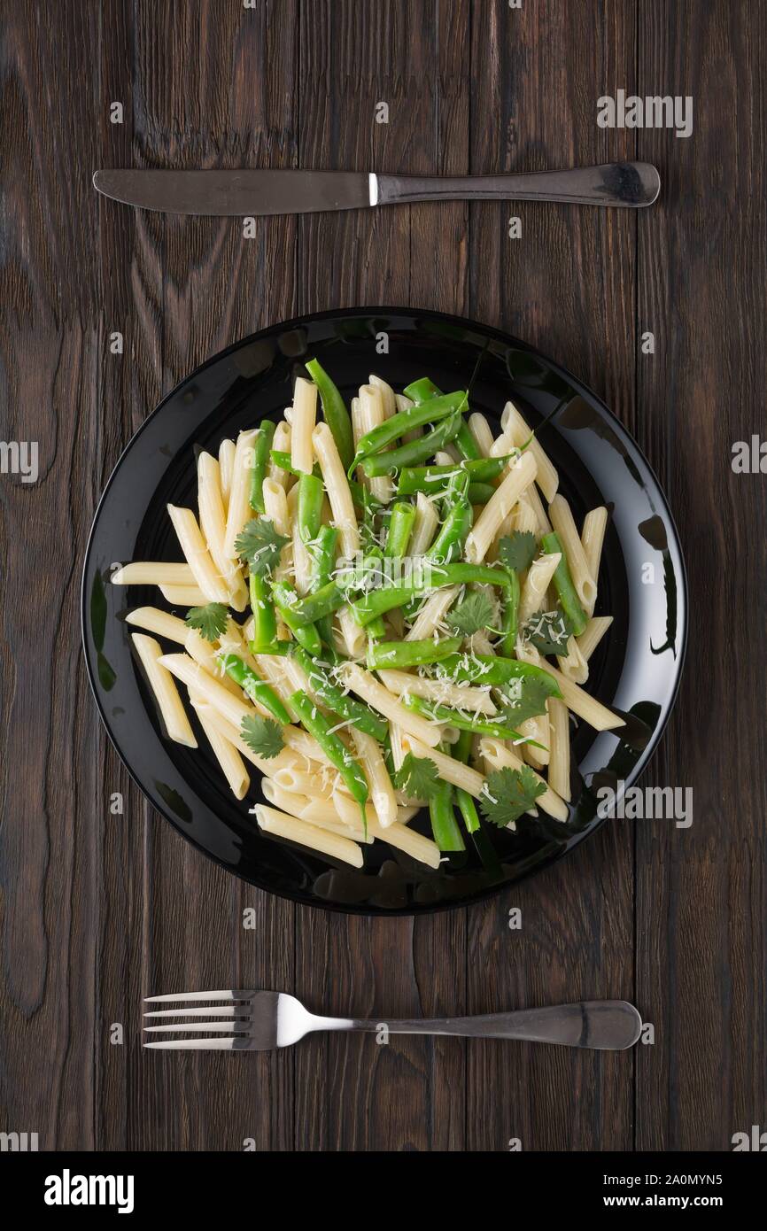 Penne pasta with green beans on a black plate. Restaurant lunch concept ...
