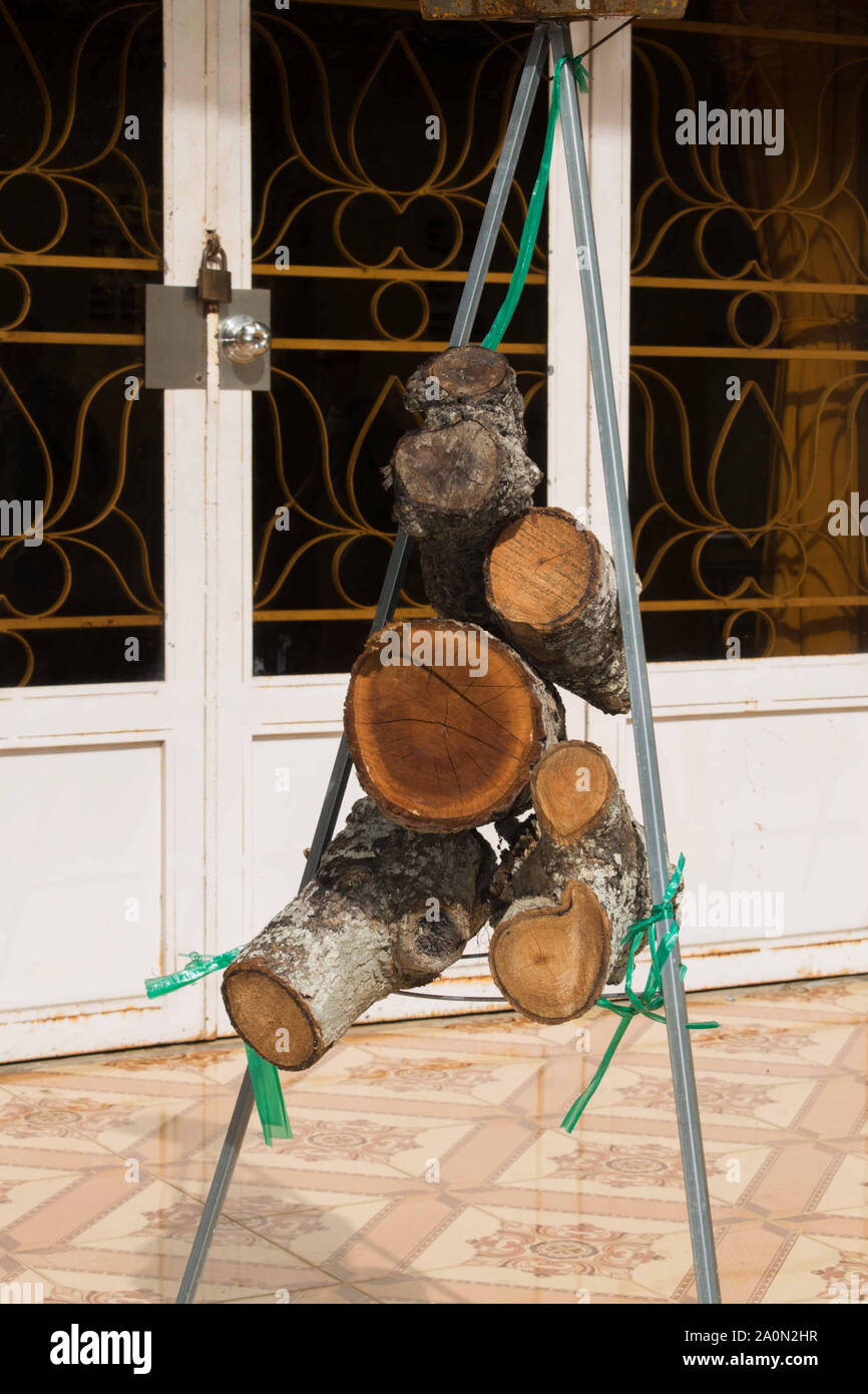 Logs used for fire placed on a triangle steel stand Stock Photo - Alamy