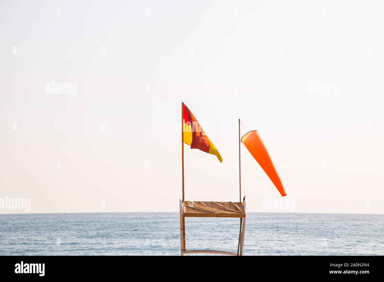Yellow-orange flag by the sea on the beach as a signal for attention to ...
