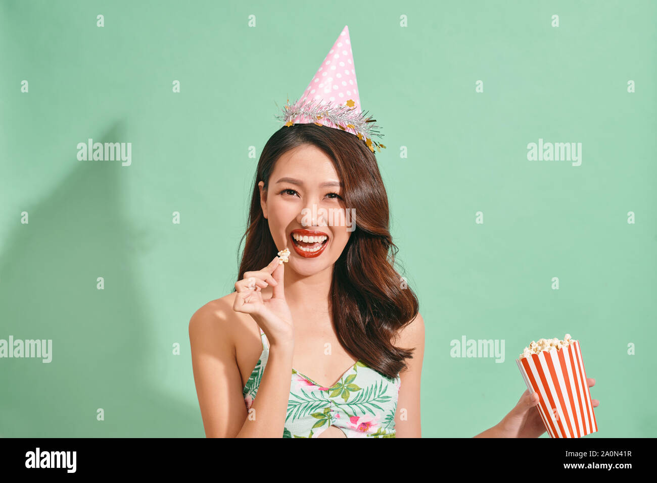 Happy woman eating popcorn on blue background Stock Photo - Alamy