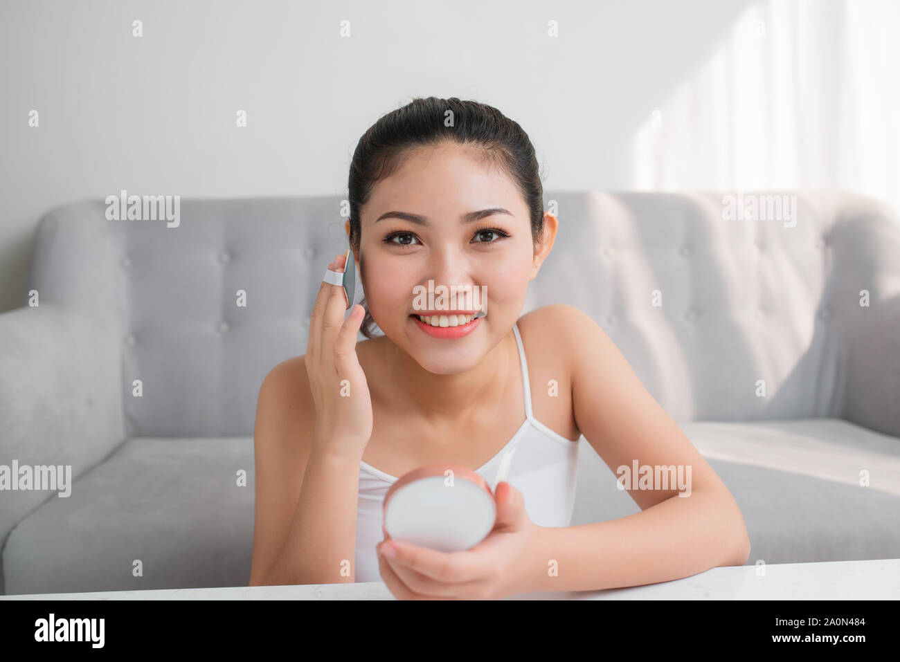 Portrait of a Beauty young woman cosmetics looking in the mirror using ...