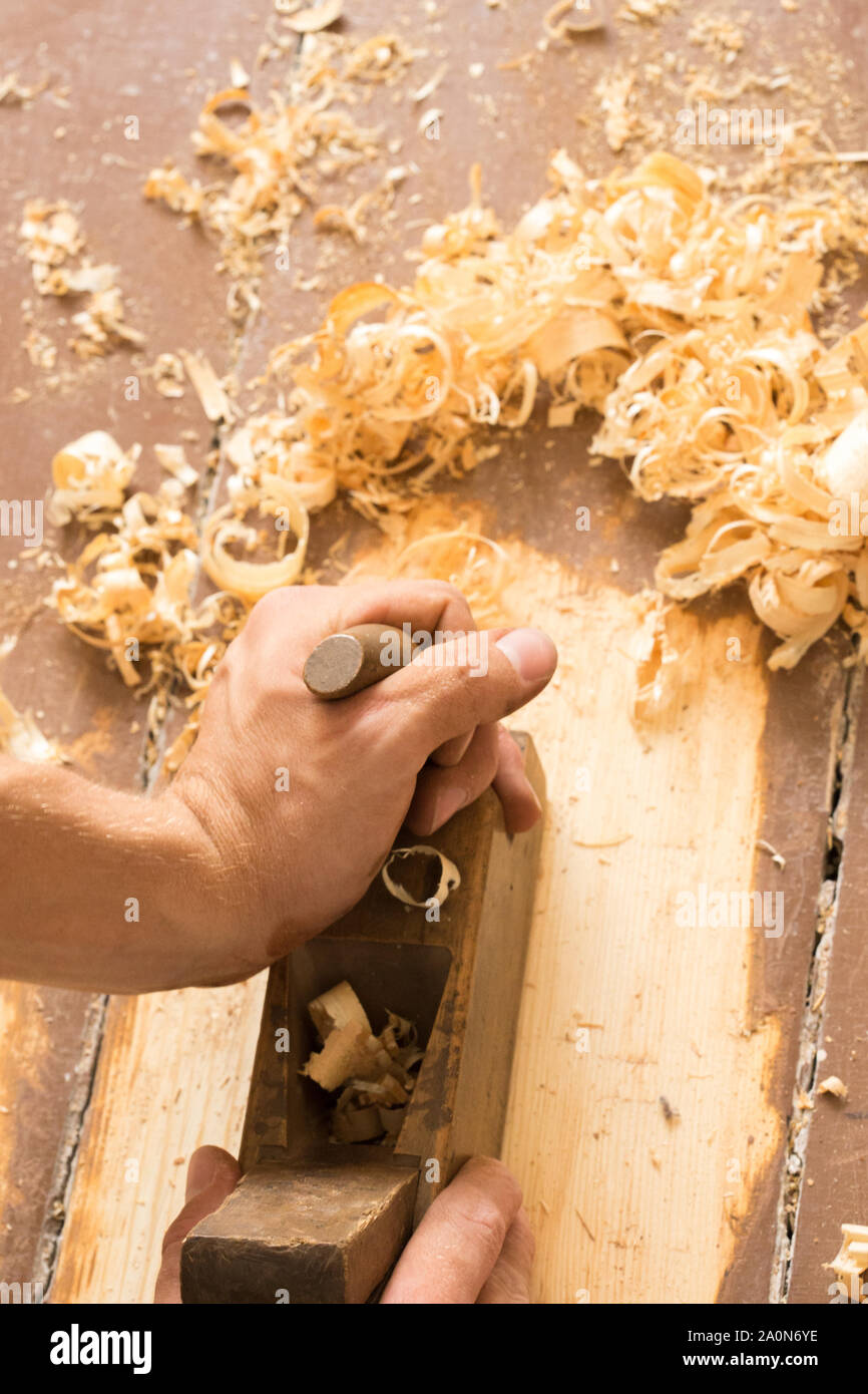 Wooden hand plane. Closeup of woodworker's hands shaving with a plane ...