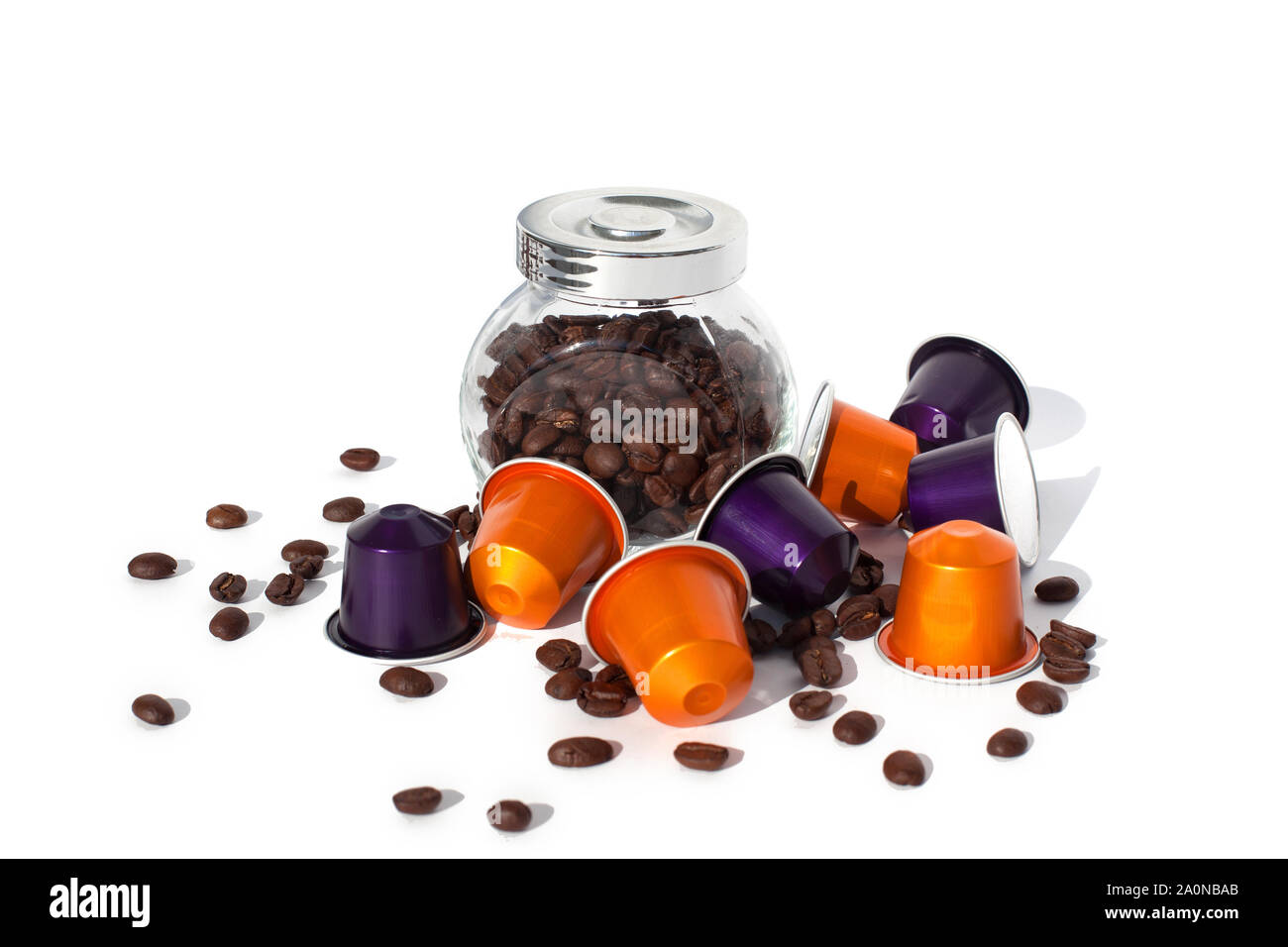 Coffee capsules and coffee beans in a glass jar on a white background ...