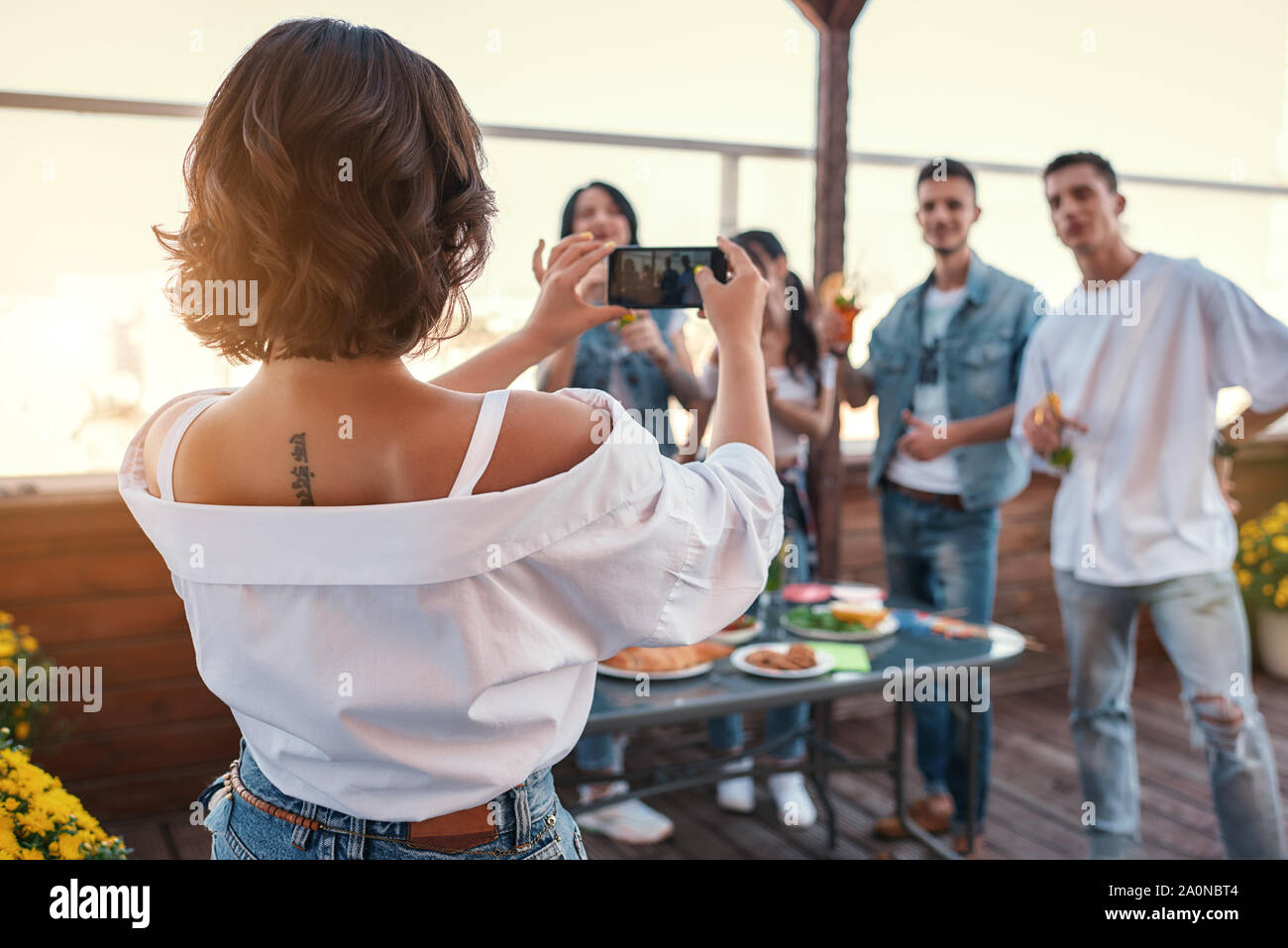 Happy memories. Back view of young woman making a photo of her friends ...