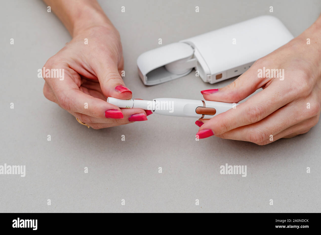 Woman's hands holds an electronic cigarette. Insert a cigarette into ...