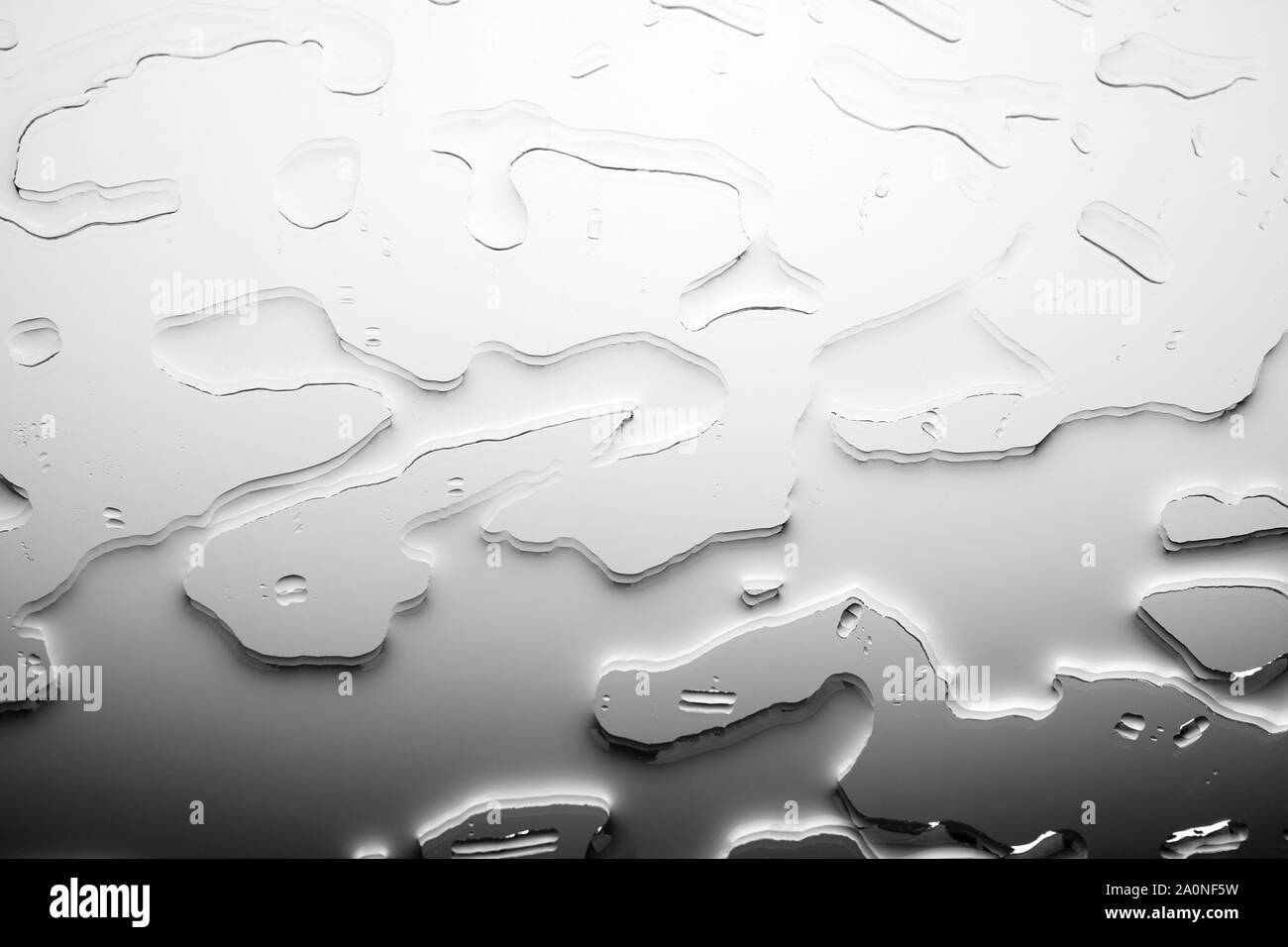 Monochrome black and white image of spilled water, glass surface in ...