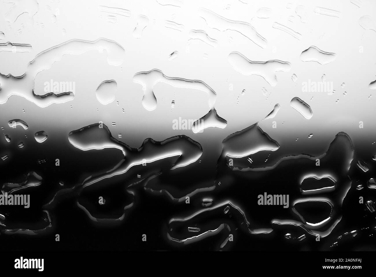 Monochrome black and white image of spilled water, glass surface in ...