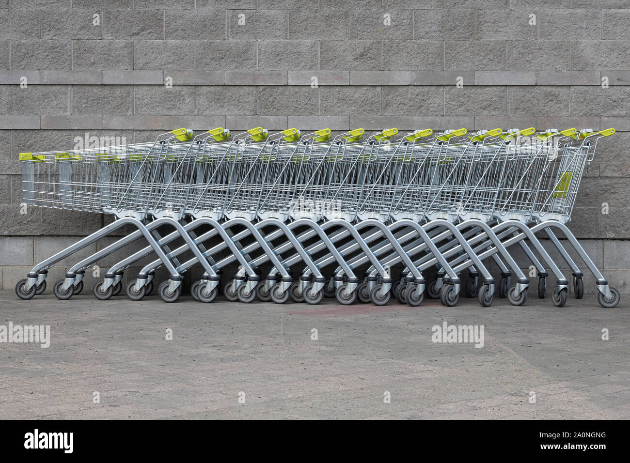 Many grocery carts with yellow handles standing in a row in the centre ...