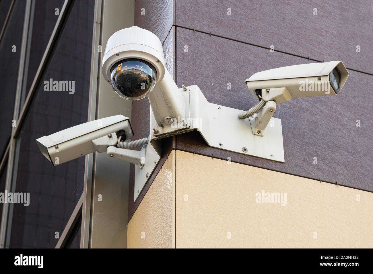 Ground view of three white surveillance cameras on office building with ...