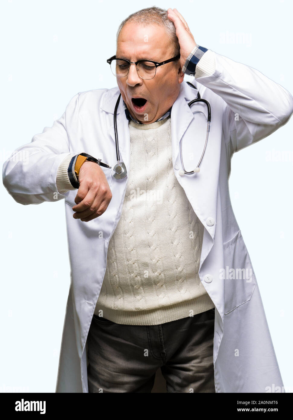 Handsome senior doctor man wearing medical coat Looking at the watch ...