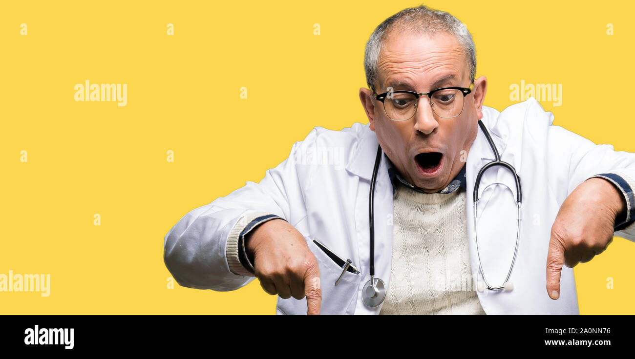 Handsome senior doctor man wearing medical coat Pointing down with ...