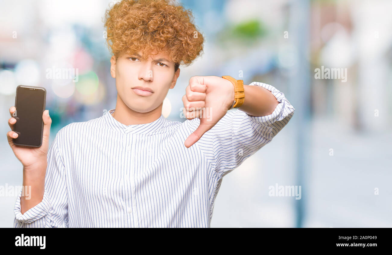 Young handsome man showing smartphone screen with angry face, negative ...