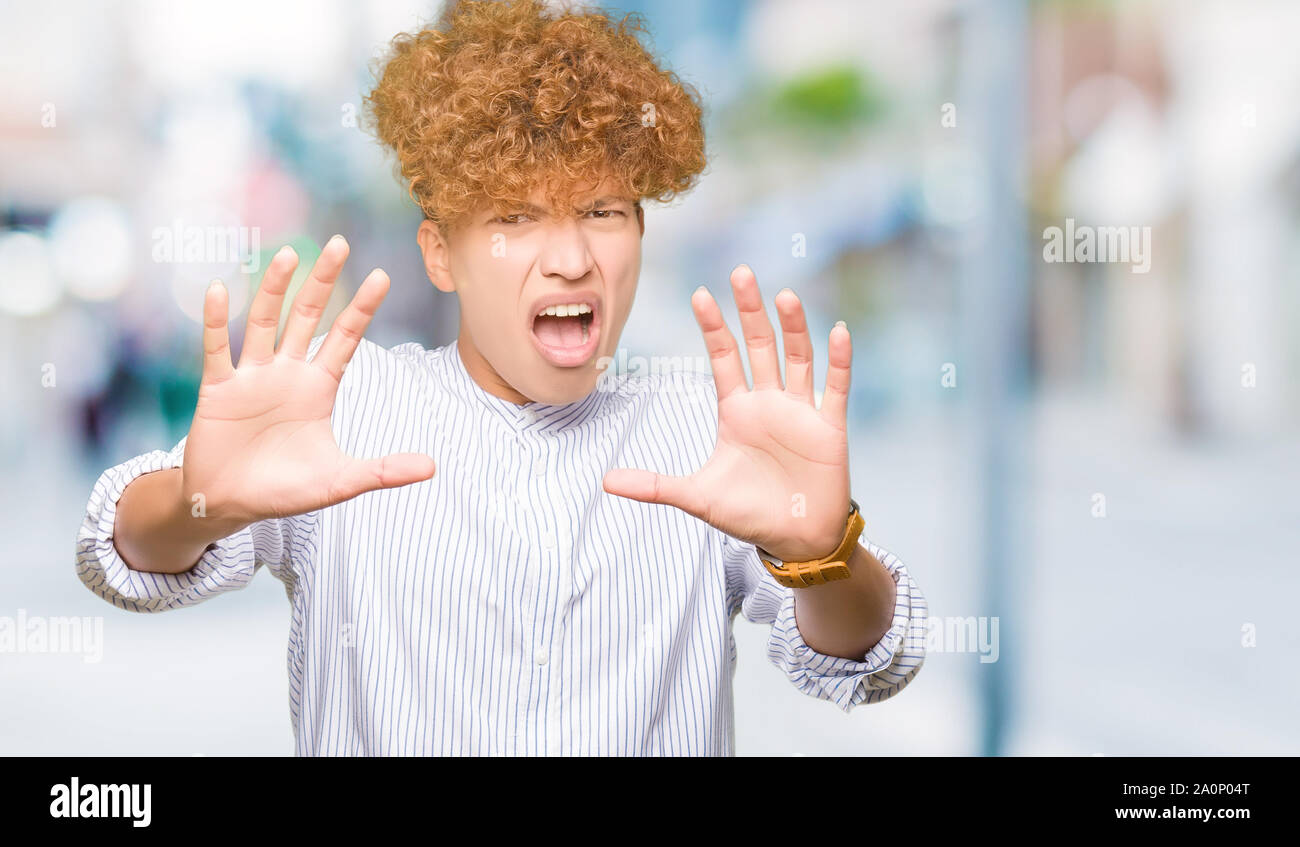 Young handsome business man with afro hair wearing elegant shirt afraid ...
