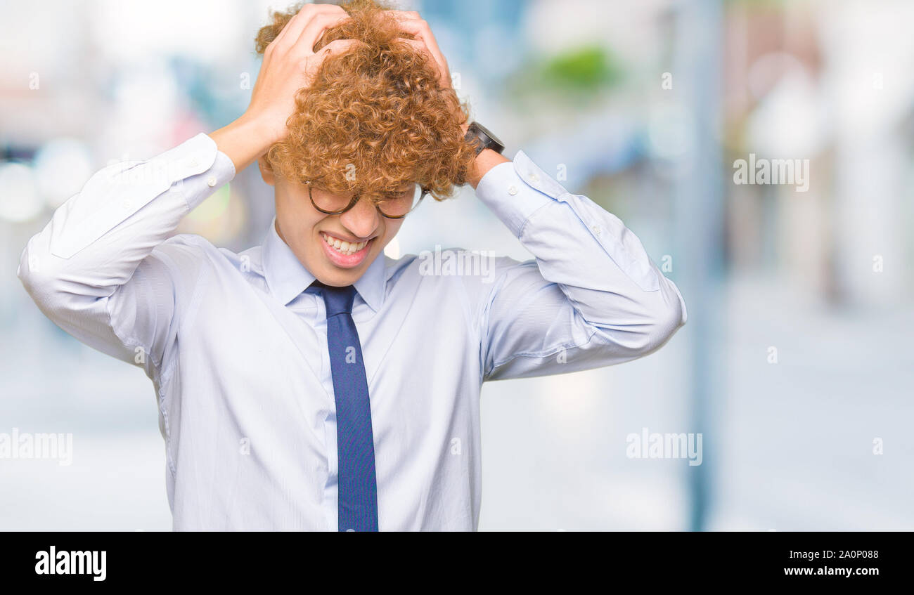 Young handsome business man with afro wearing glasses suffering from ...